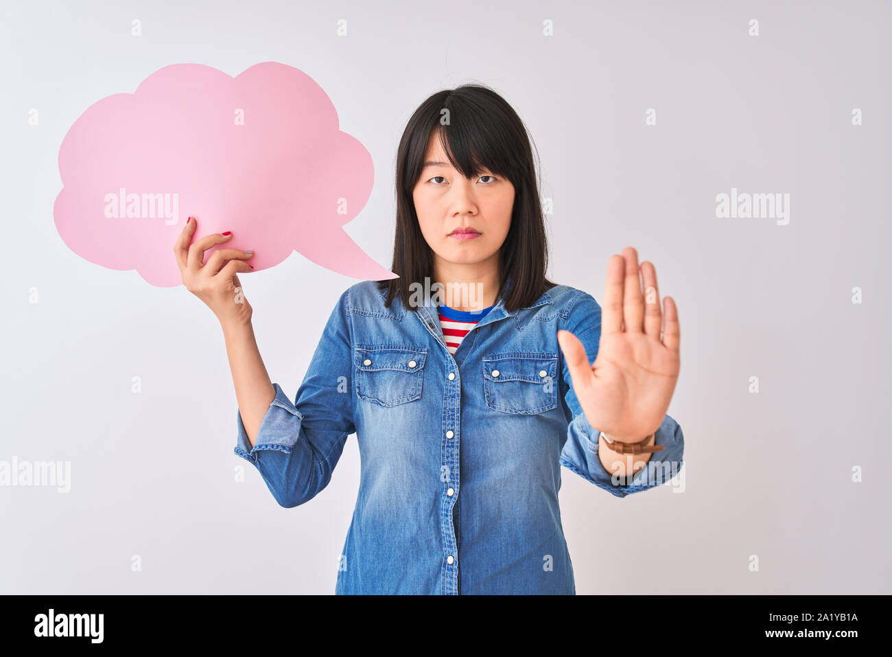Young beautiful Chinese woman holding cloud speech bubble over isolated ...