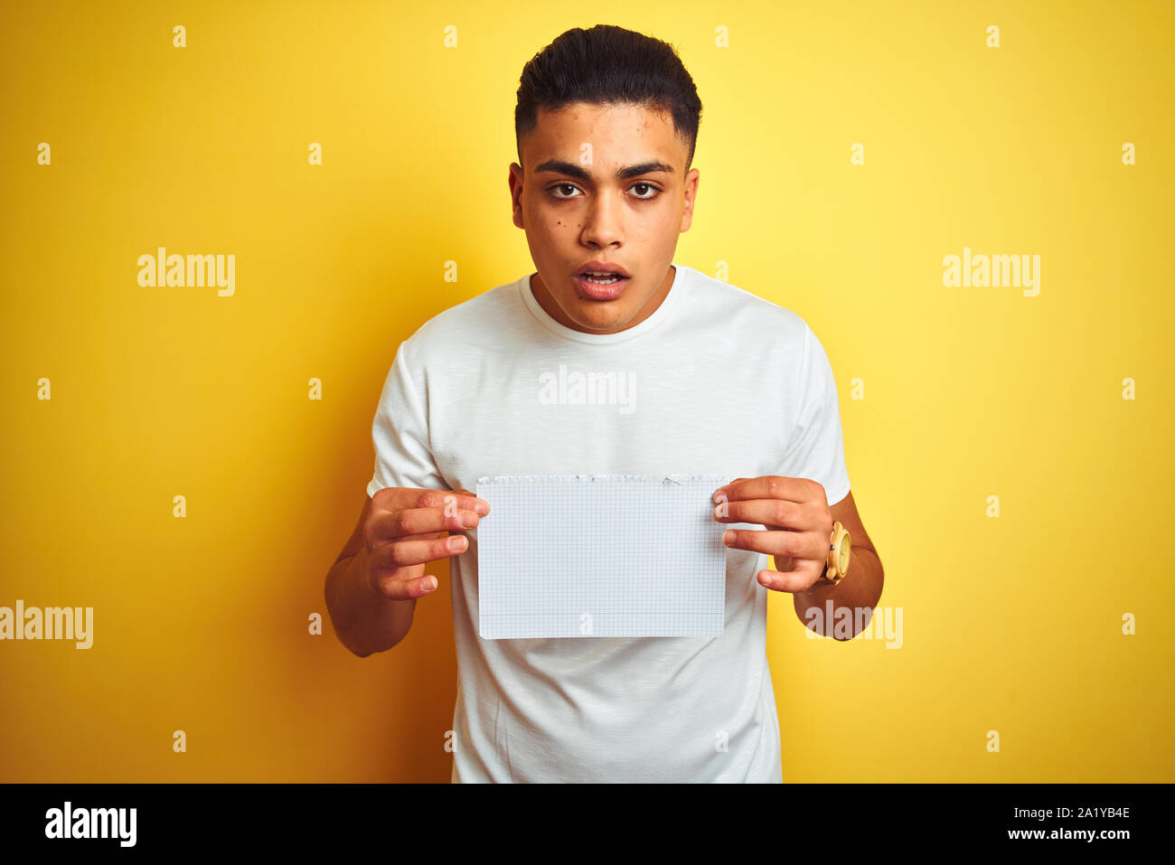 Young brazilian man showing paper banner standing over isolated yellow ...