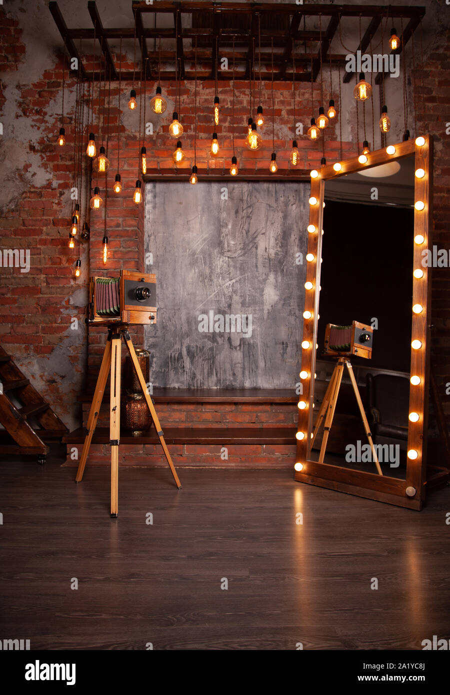 a very old rarity photo camera stands on a tripod near a huge mirror ...