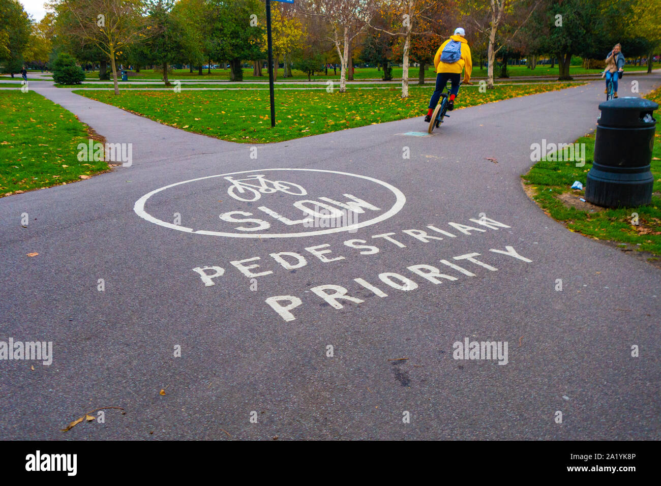 Cyclist riding over a pedestrian priority warning sign on a park ...