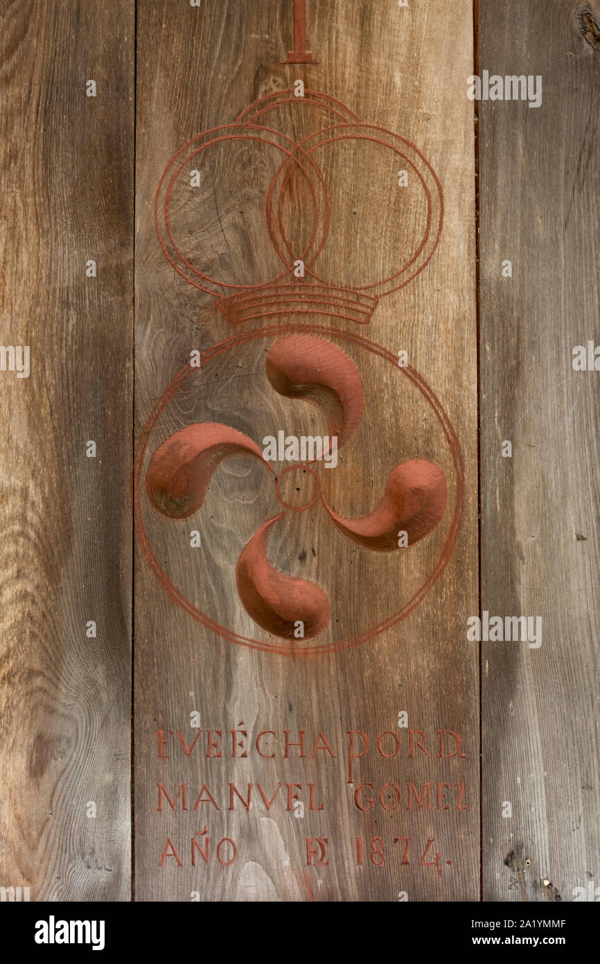 A Basque cross (lauburu) and inscription adorn a traditional palloza at ...