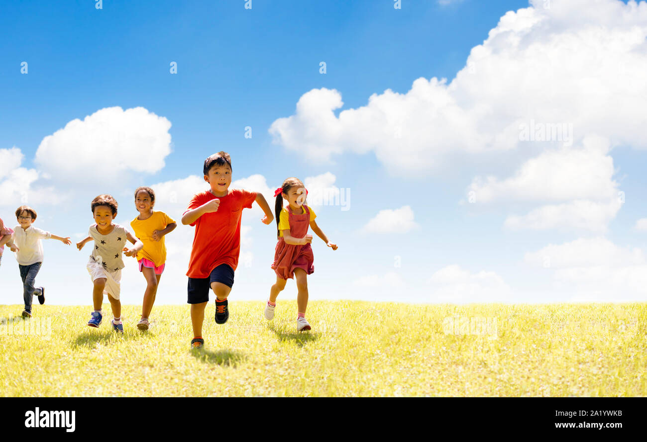 Multiethnic group of school children running on the grass Stock Photo ...