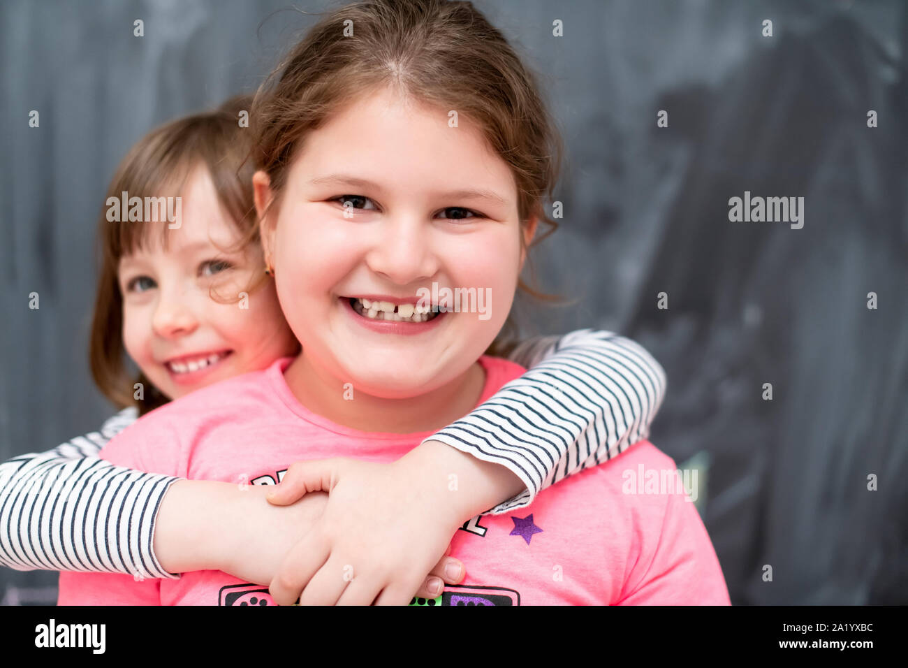 portrait of two happy cute little girls hugging each other while having ...