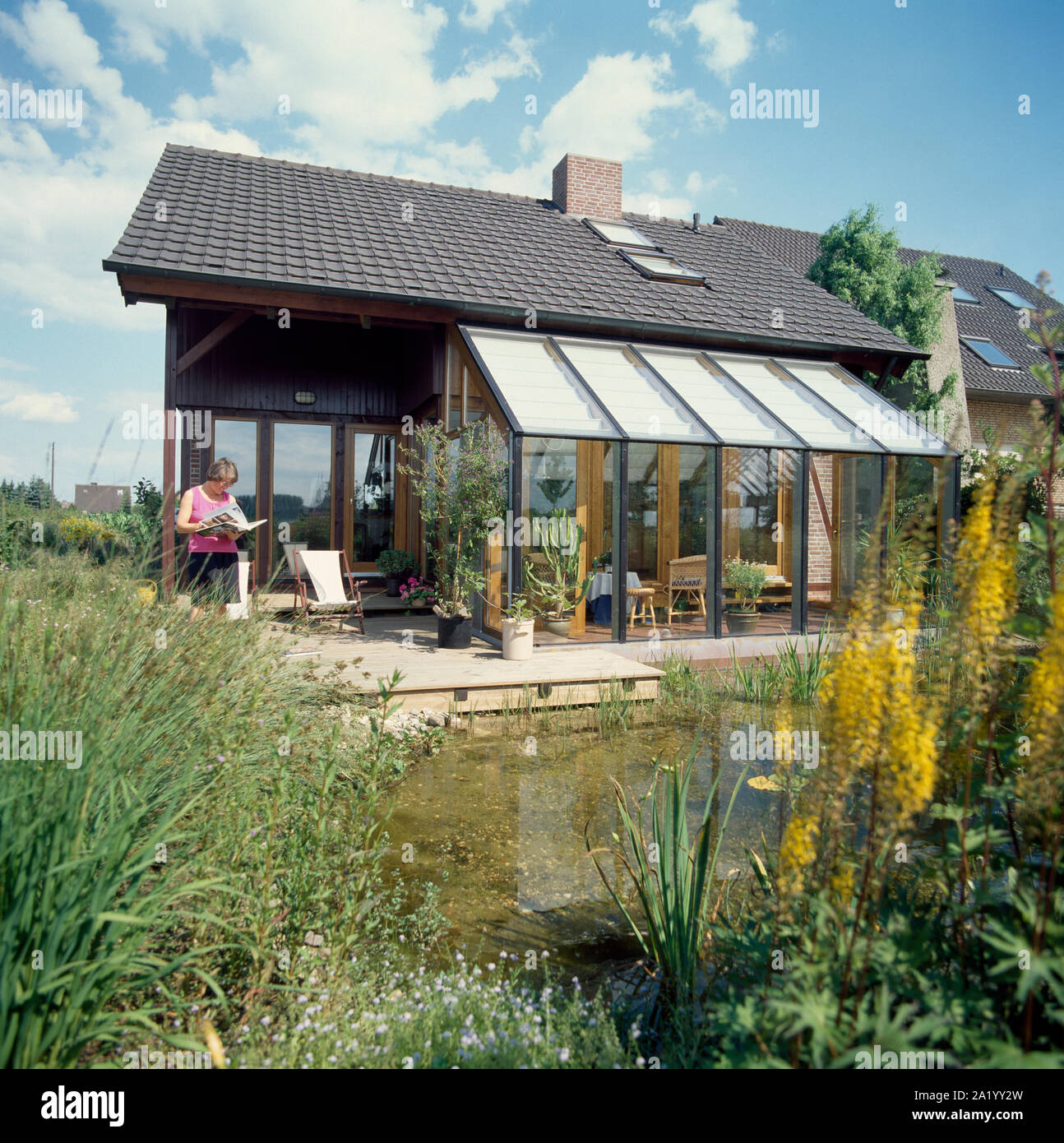 Modern glazed extension in front of large decking area to pond ...