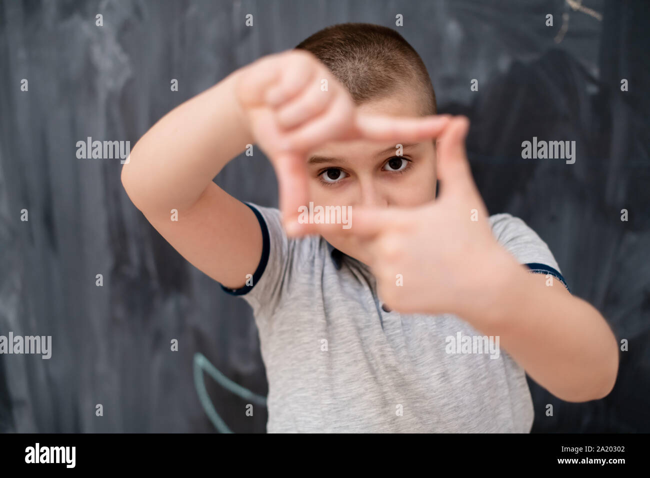 happy cute little boy having fun making hand frame gesture while ...