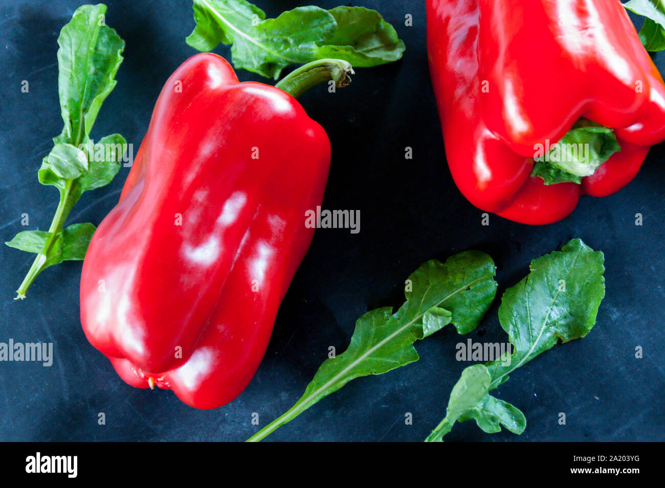 res peppers and arugula leaves over a black rustic background Stock ...