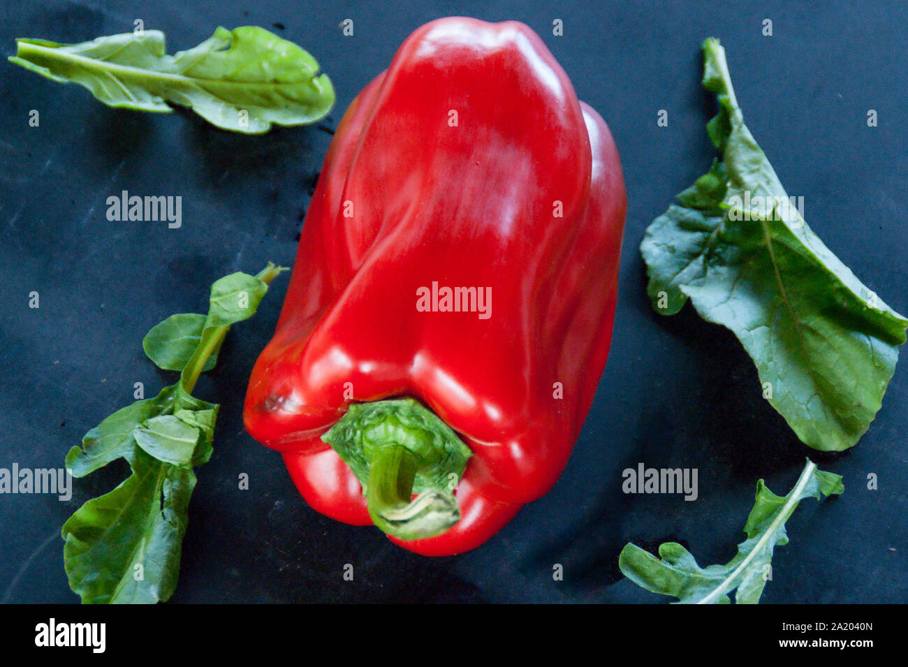 res pepper and arugula leaves over a black rustic background Stock ...