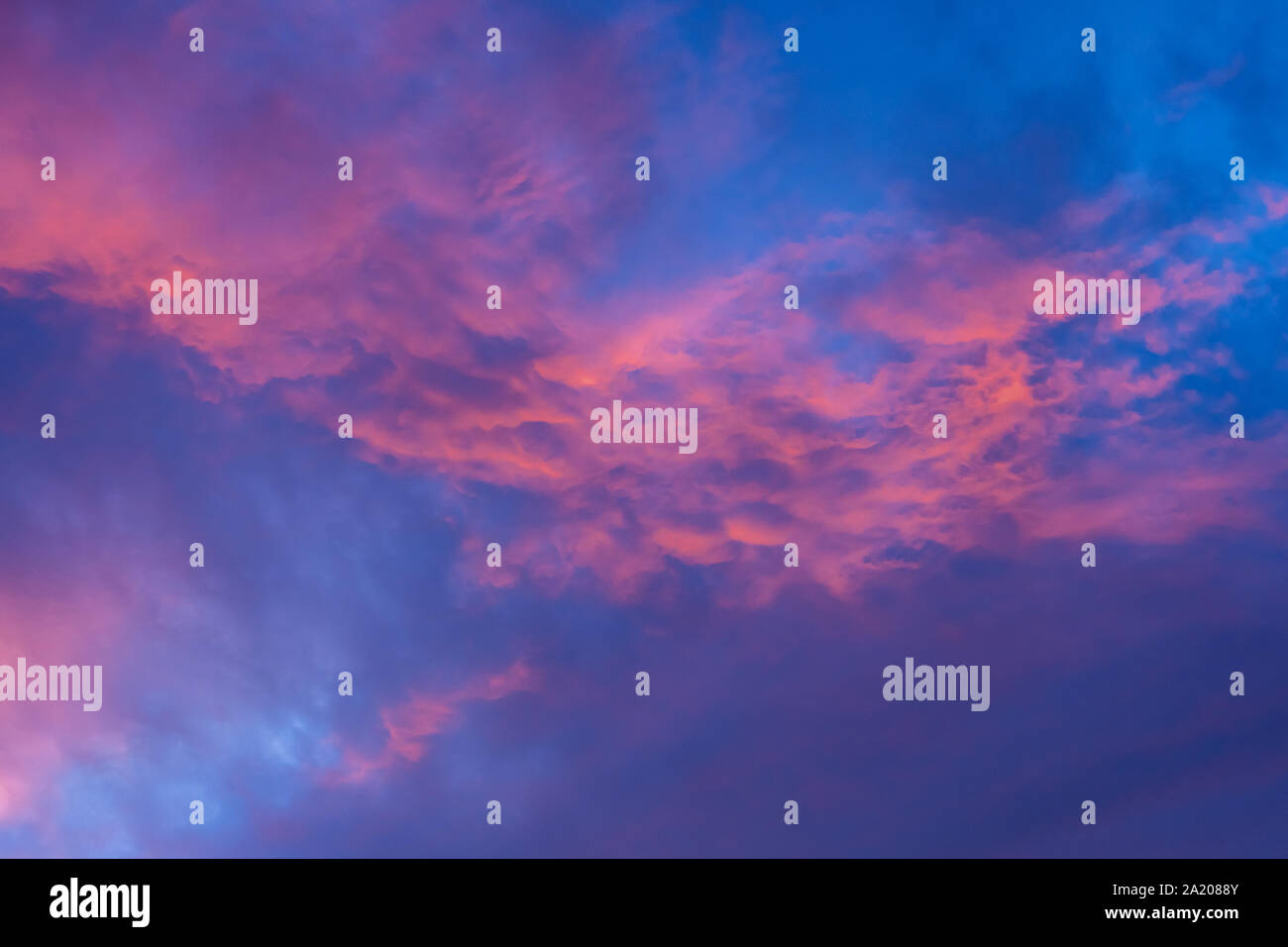 Violet clouds in a dramatic sunset over mountains Stock Photo - Alamy