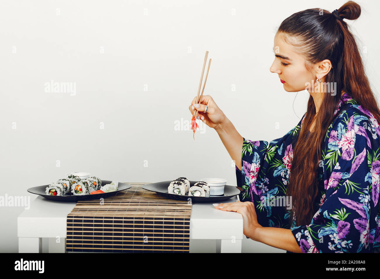Beautiful girl eating a sushi in a studio Stock Photo - Alamy