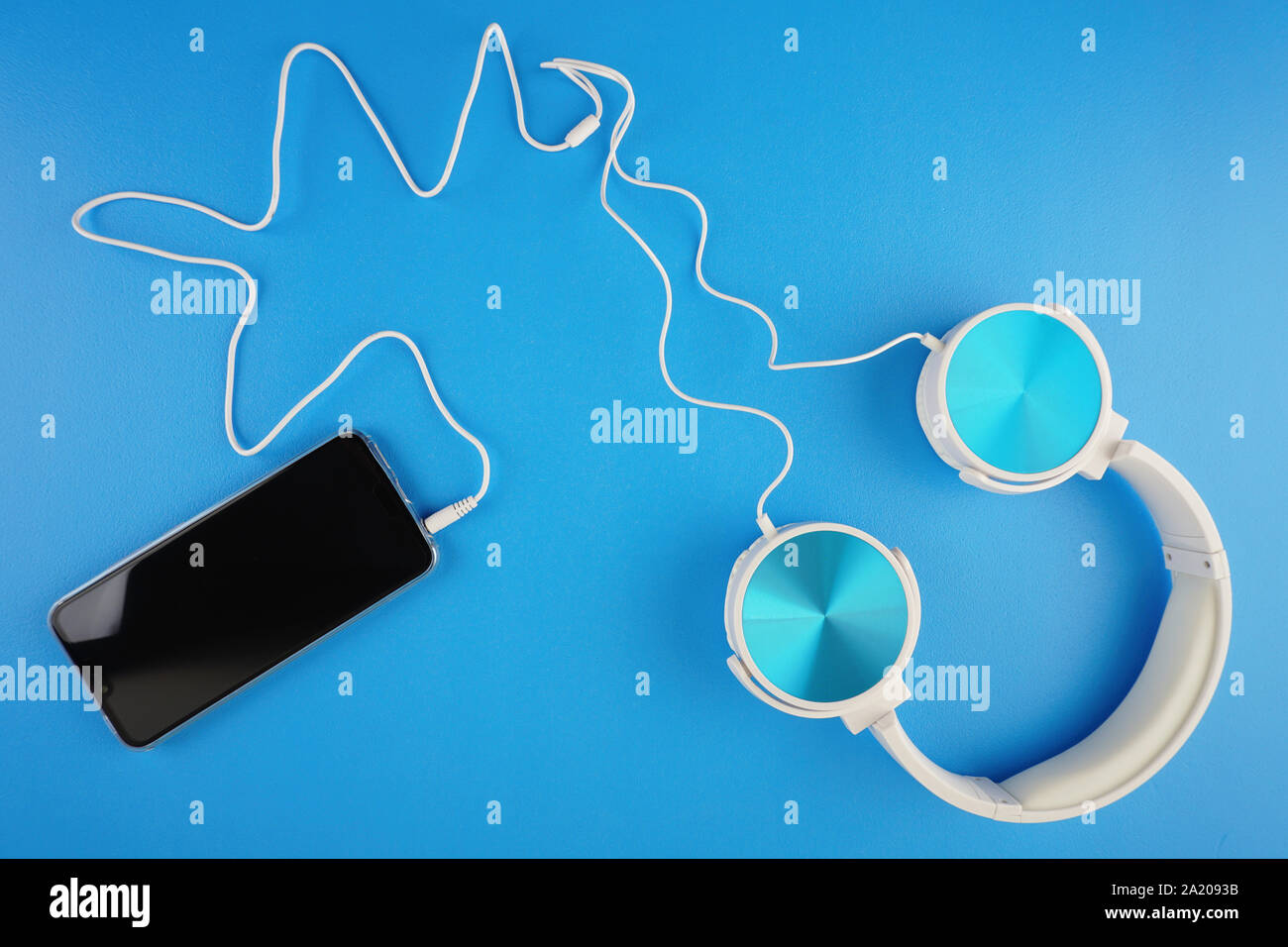 blue white color headphone placed next to handphone on a blue ...