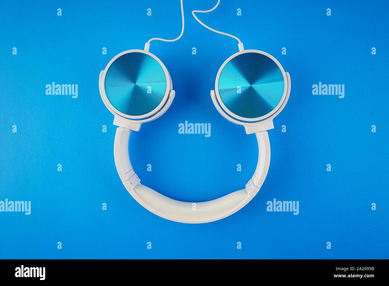 blue white color headphone on a blue background Stock Photo - Alamy