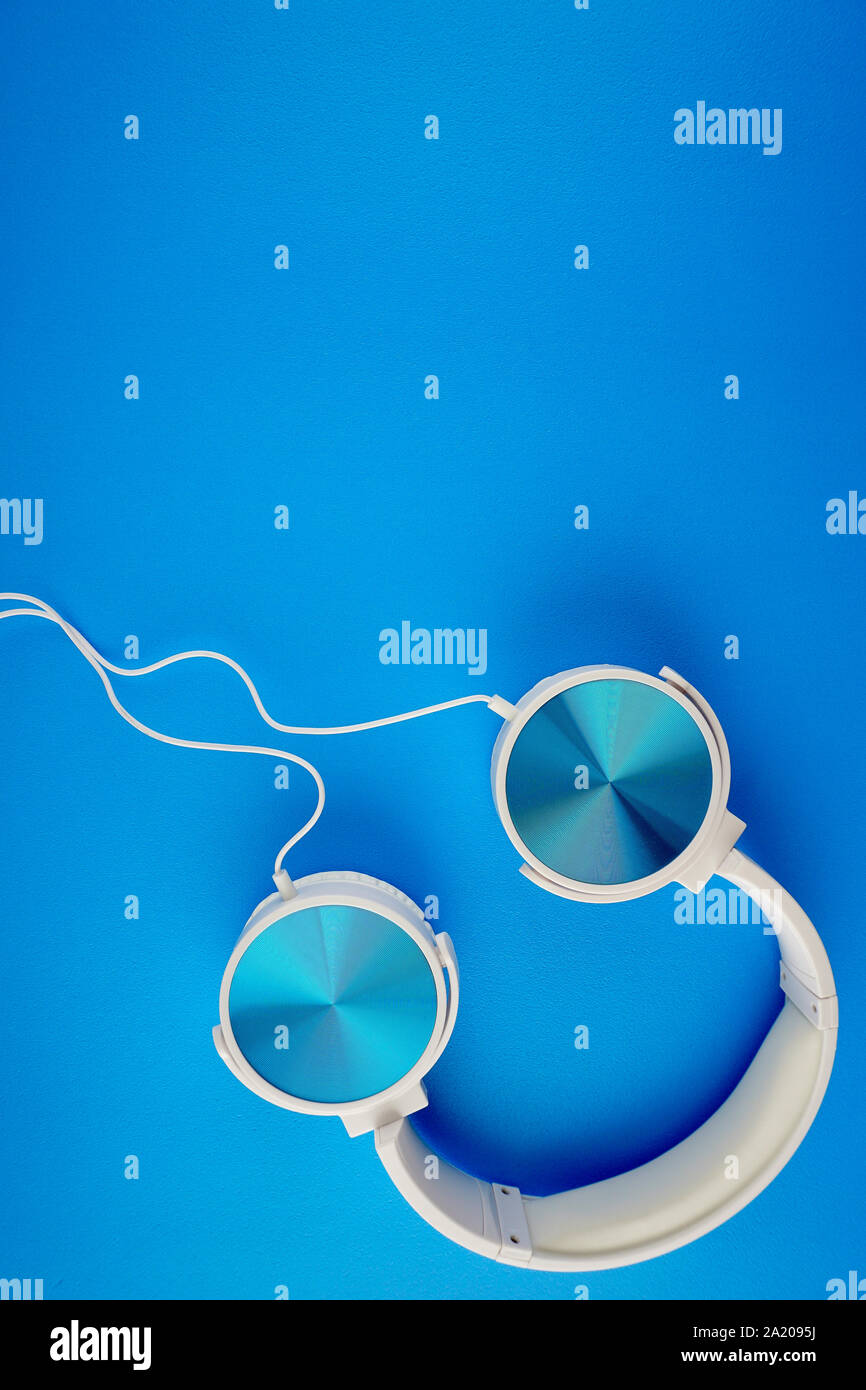blue white color headphone on a blue background Stock Photo - Alamy