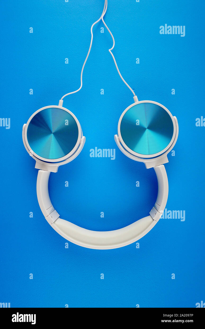 blue white color headphone on a blue background Stock Photo - Alamy