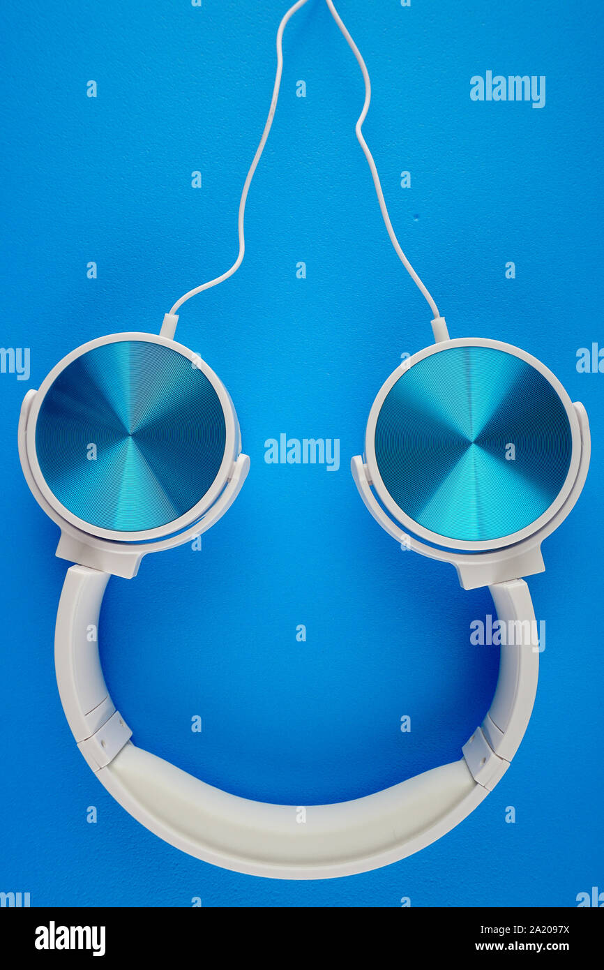 blue white color headphone on a blue background Stock Photo - Alamy