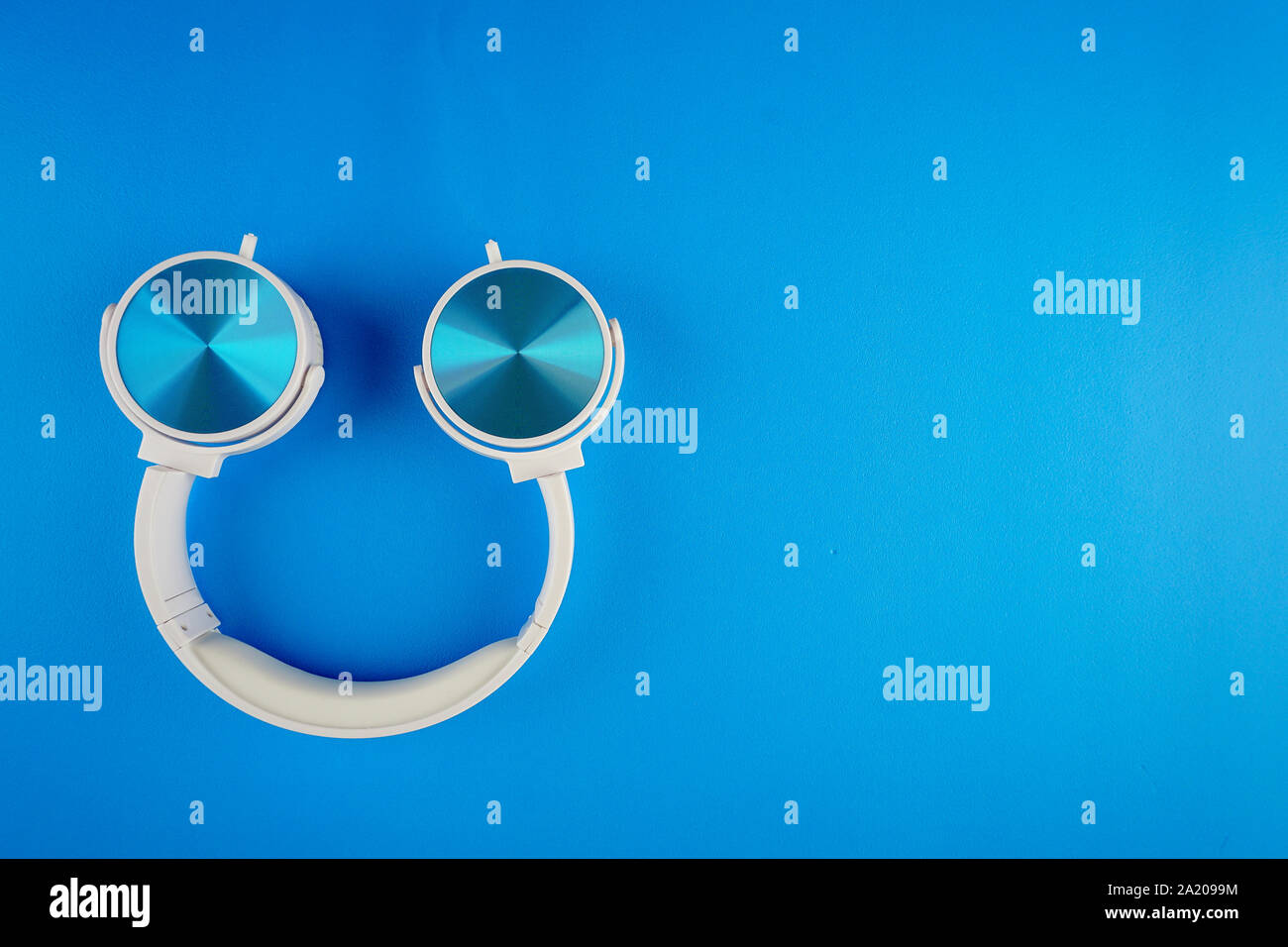 blue white color headphone on a blue background Stock Photo - Alamy