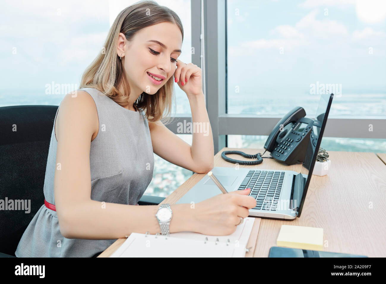 Beautiful manager writing her creative ideas in planner when working on ...