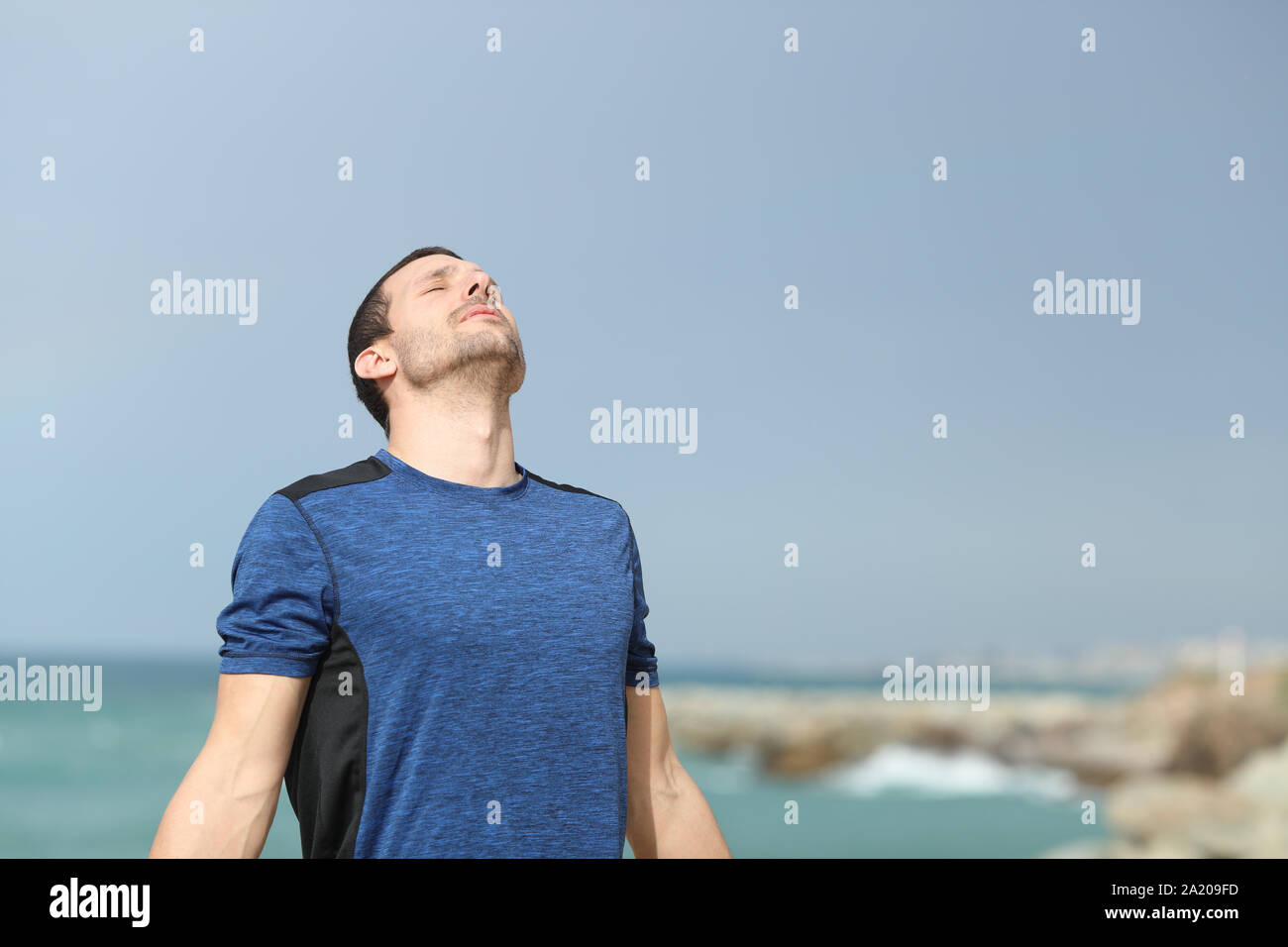 Serious runner breathing deeply fresh air on the beach after sport ...