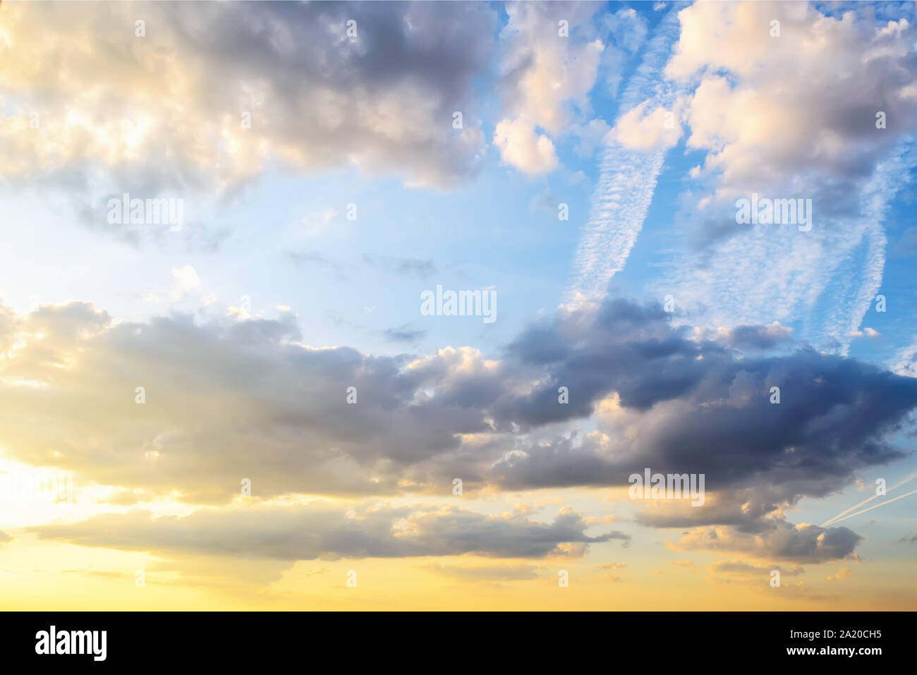 Evening skyscape with wide airplane traces. Blue sky and clouds are ...