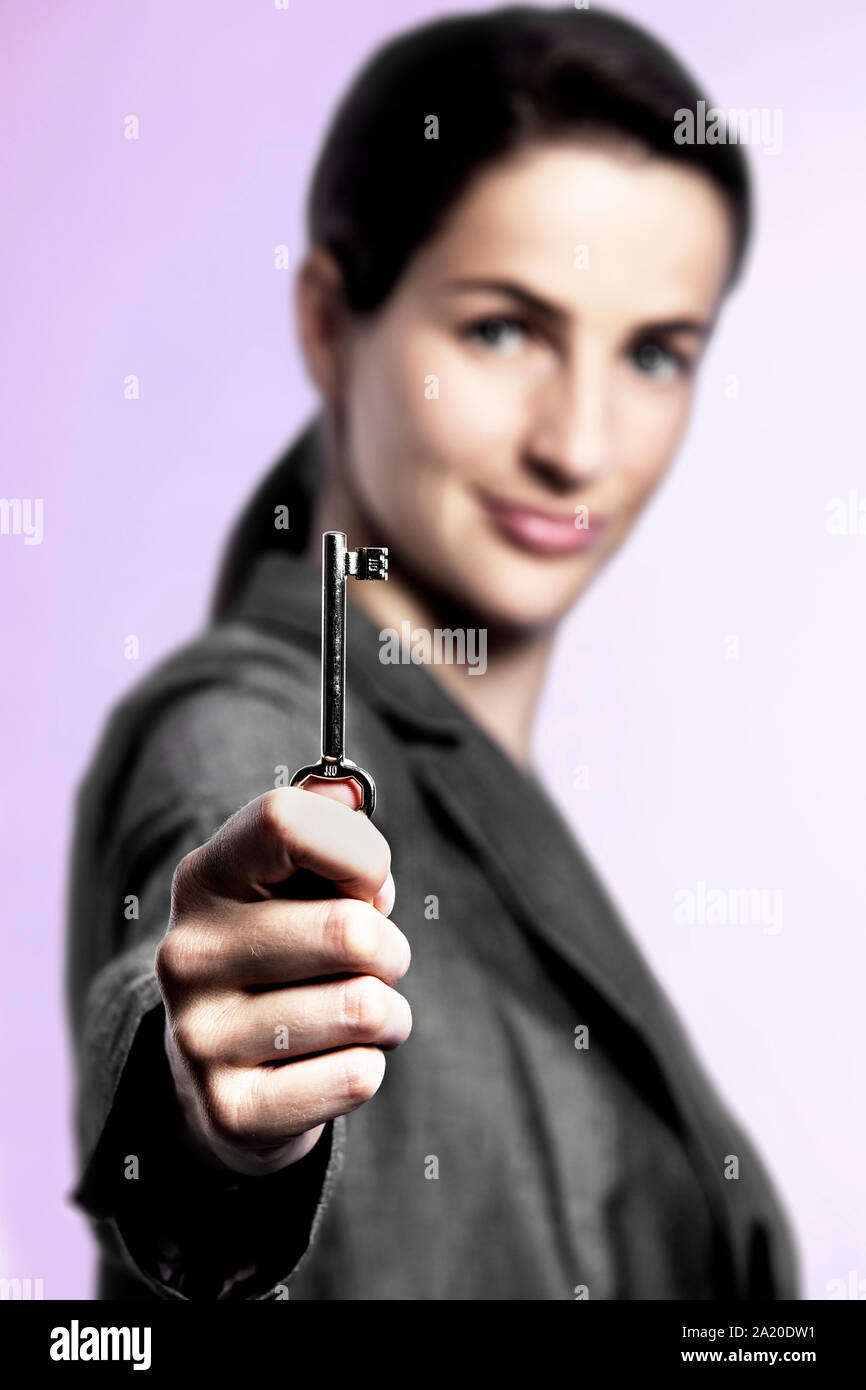 Key to success, business woman holding key upright between fingers ...