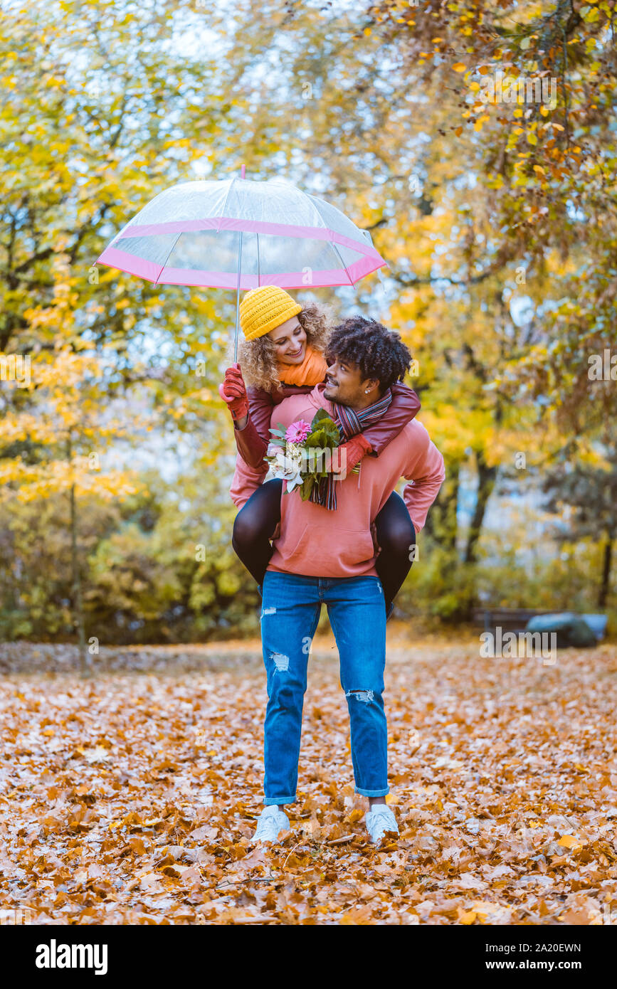 Black man carrying his Caucasian girl piggyback in fall Stock Photo - Alamy