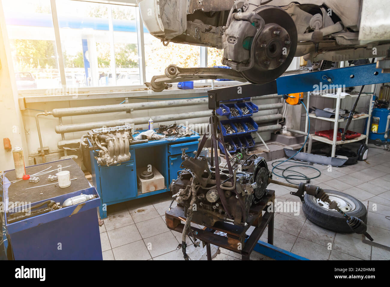 An old used car without wheel, raised on a lift for repair and under it ...