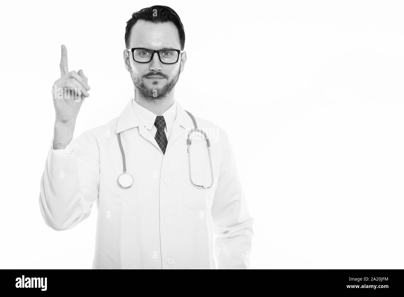 Studio shot of young man doctor pointing finger up Stock Photo - Alamy