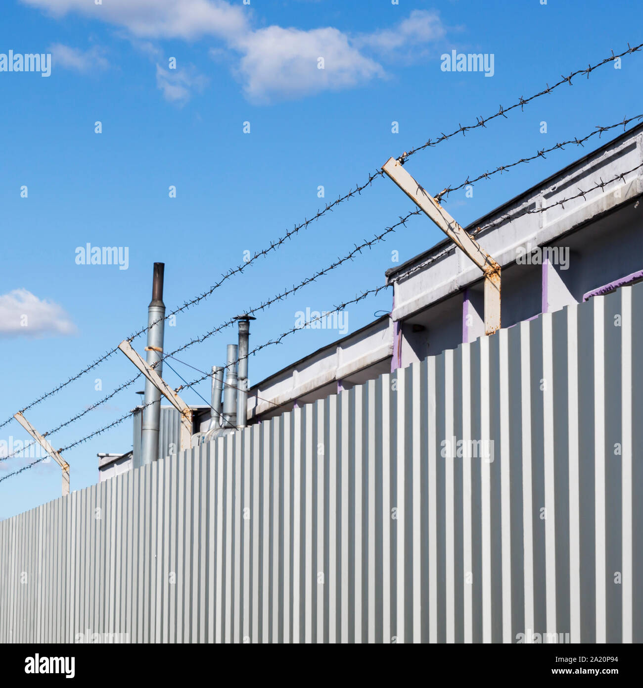 Barbed wire stretched in three threads over a metal fence of gray ...