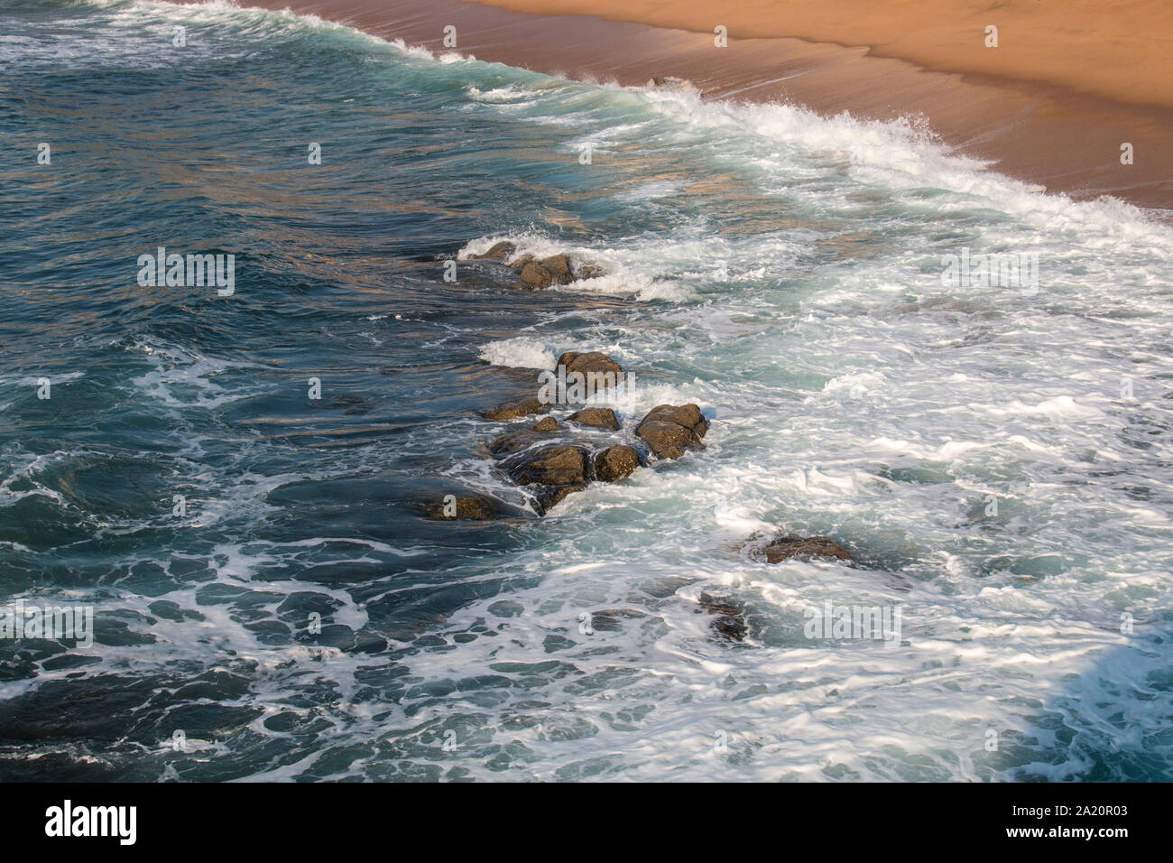 Rocks exposed in the shall water as a wave break on the shore Stock ...
