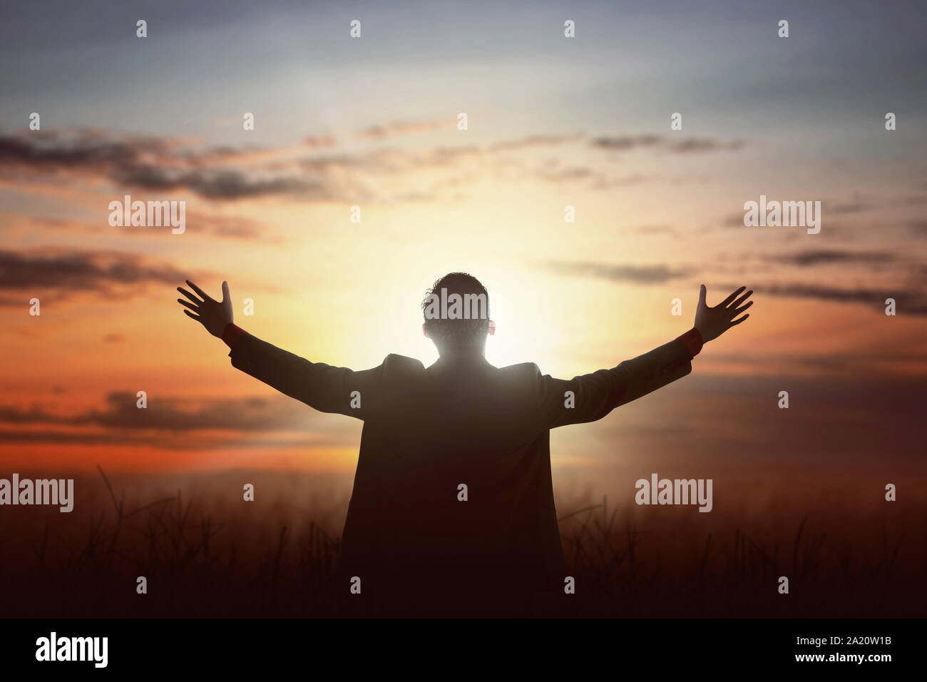 Rear view of Asian businessman raised hands and praying to god with a ...