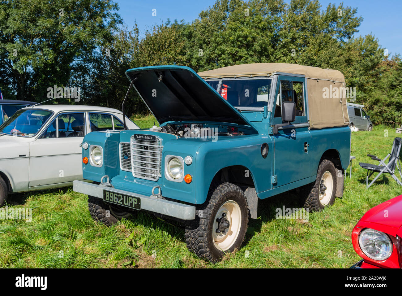 A classic Landrover Defender with its bonnet open seen from the front ...
