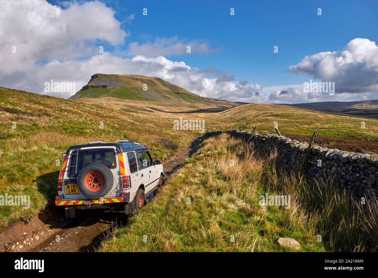 Car on unsurfaced road near Helwith Bridge with Pen y Ghent beyond ...
