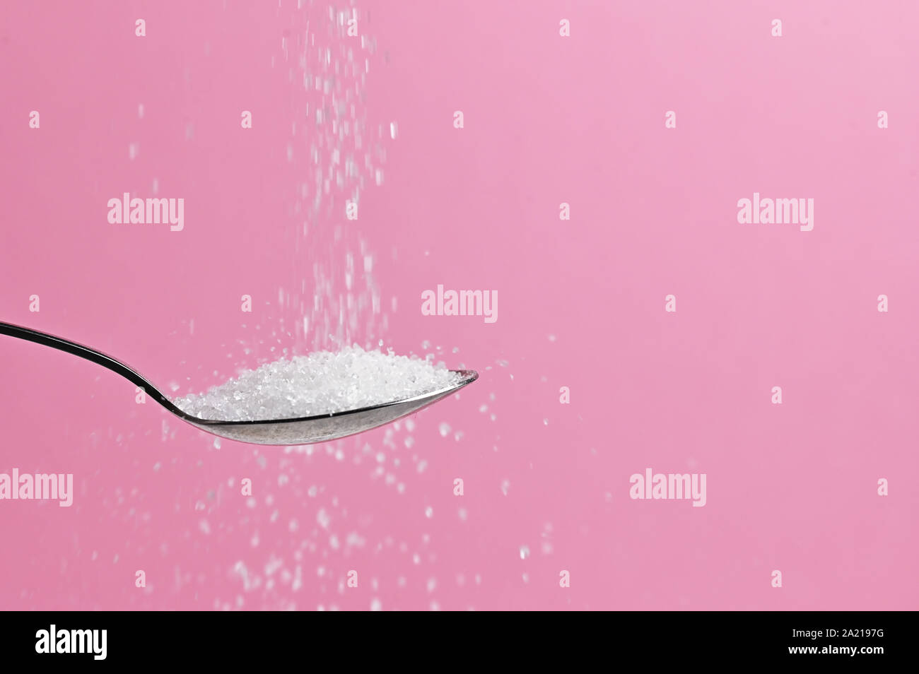 White Sugar Pouring From A Spoon Stock Photo - Alamy