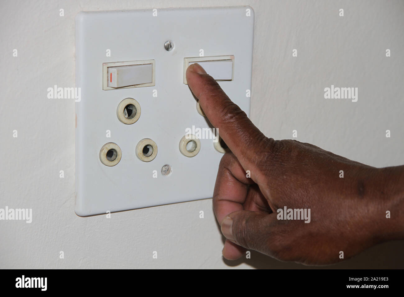 Close-up of hand switching off a white double power socket, South ...