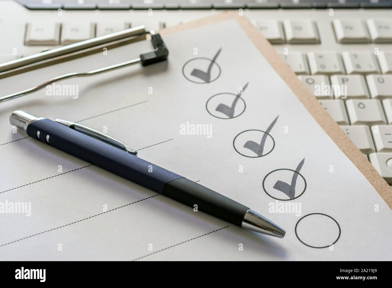 Checking off completed tasks at a desk workplace with computer keyboard ...