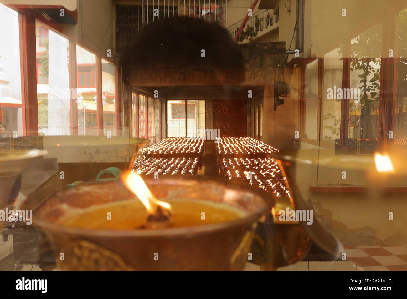Close up of a lamp flame and Series of small oil lamps in a Tibetan ...