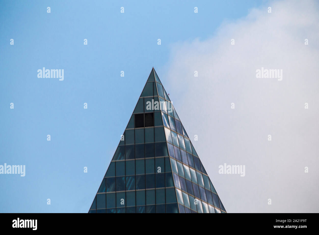 Sharp pointed peak of an office building tearing up the blue sky. Large ...