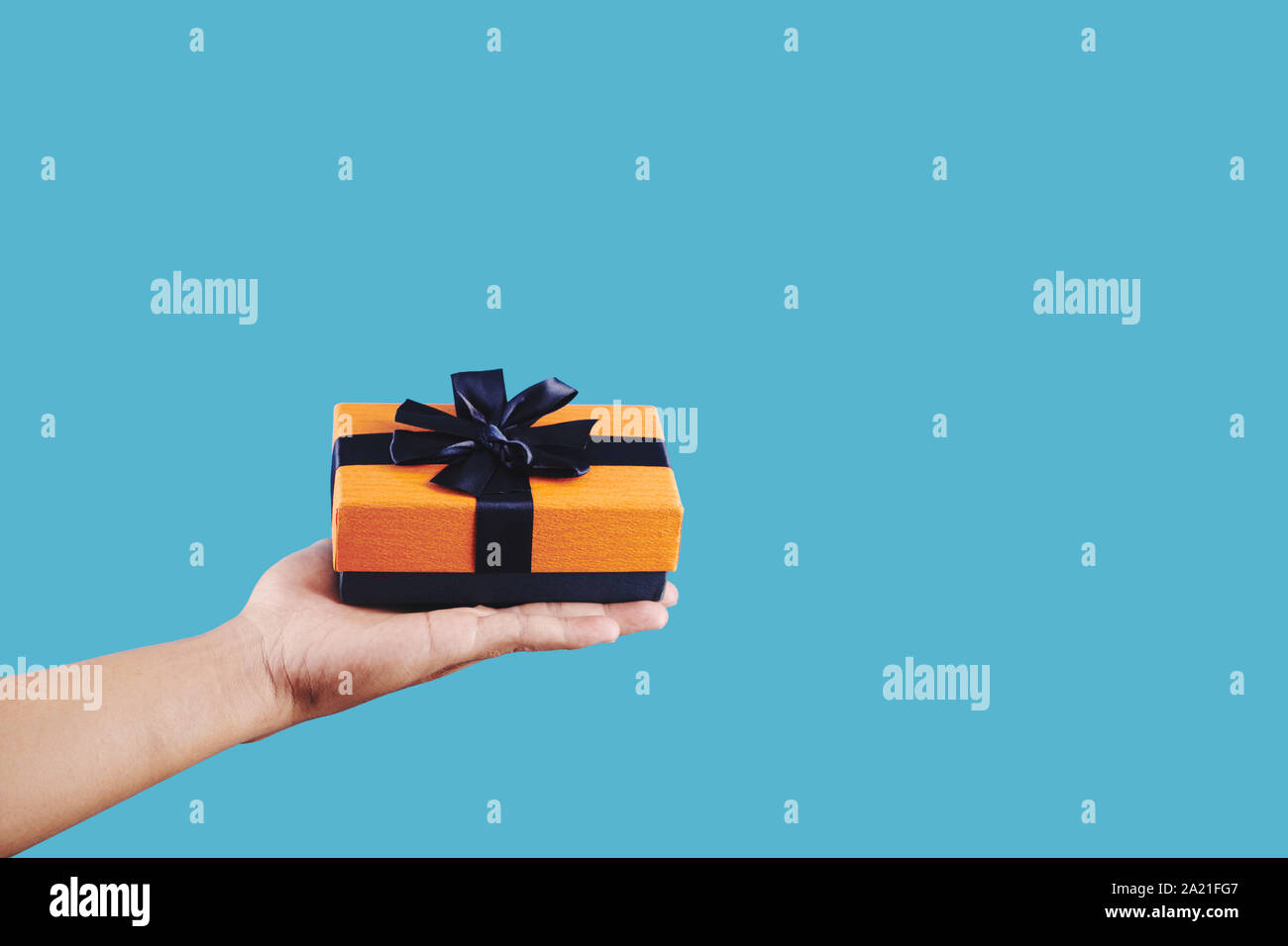 Hand with present wrapped in blue and orange paper with big bow Stock ...