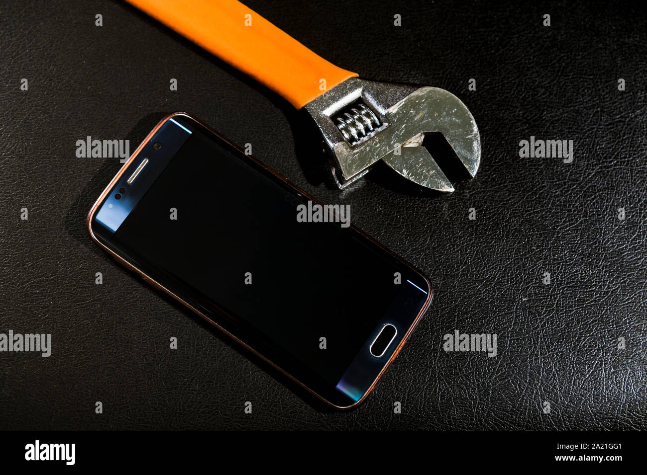 Top view close up of an adjustable wrench with a smart phone on black ...