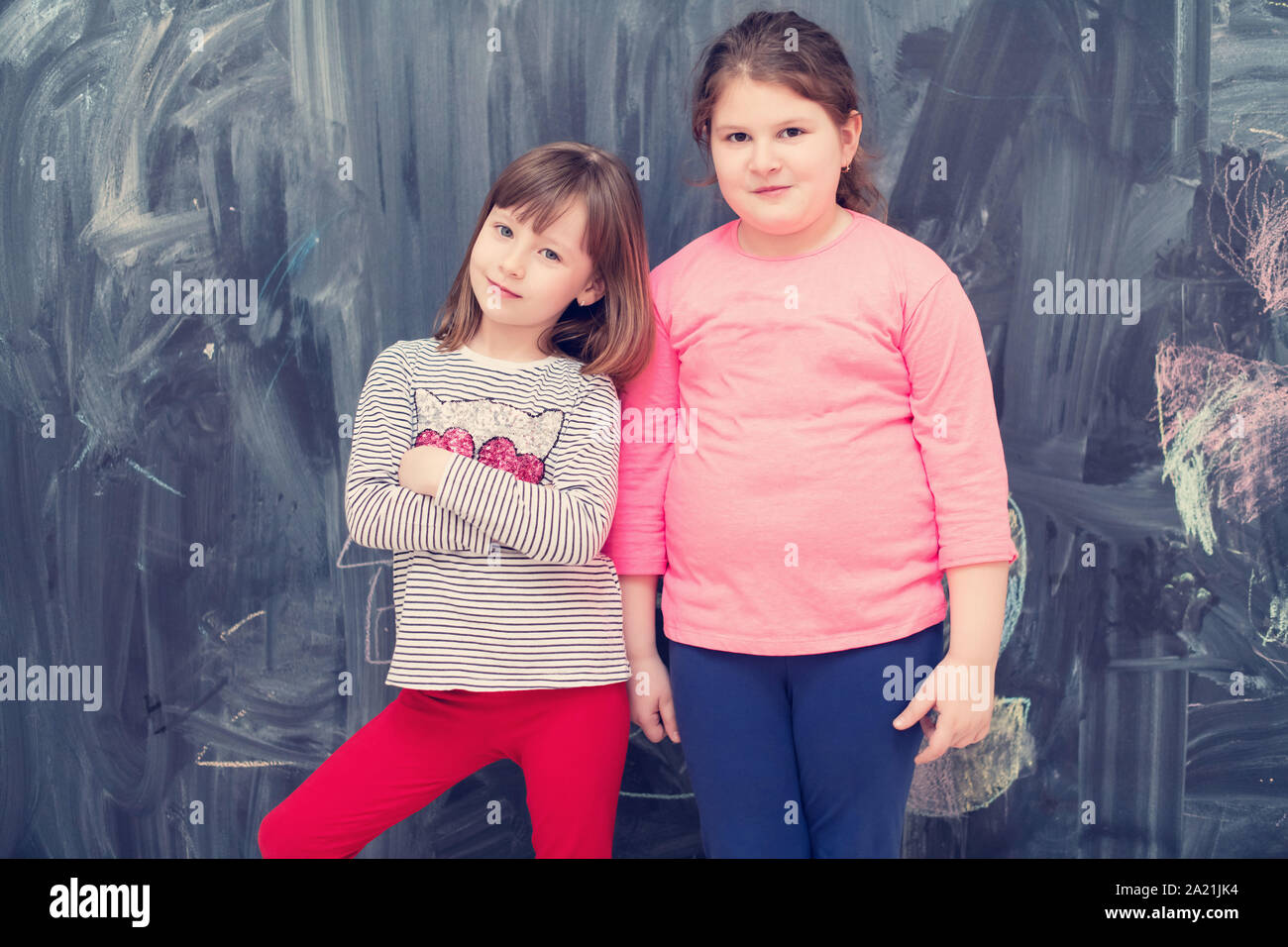 portrait of two happy cute little girls standing in front of black chalkboard Stock Photo - Alamy