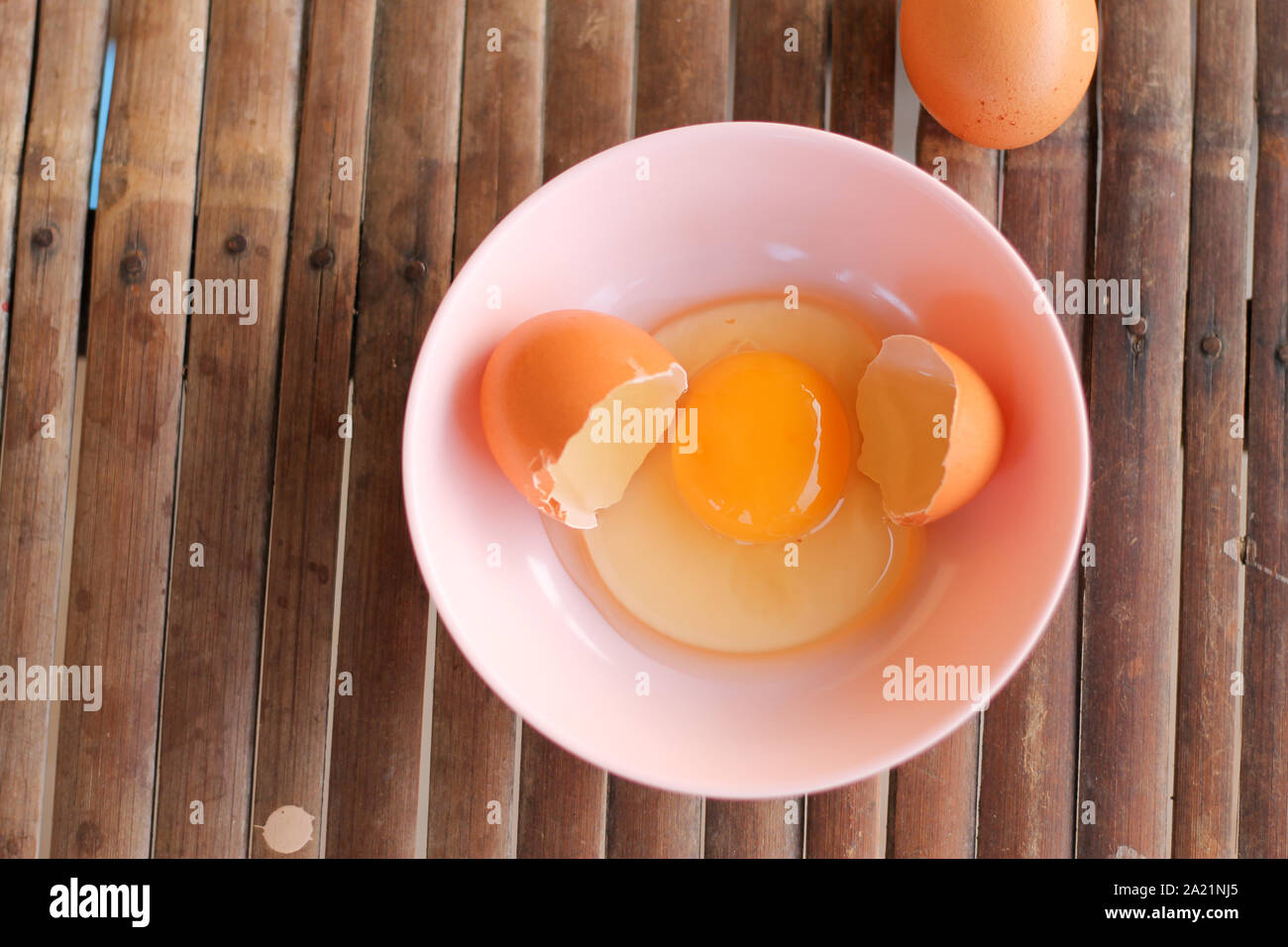 shell with egg and open Eggs in a pink bowl on Bamboo battens. Top view ...