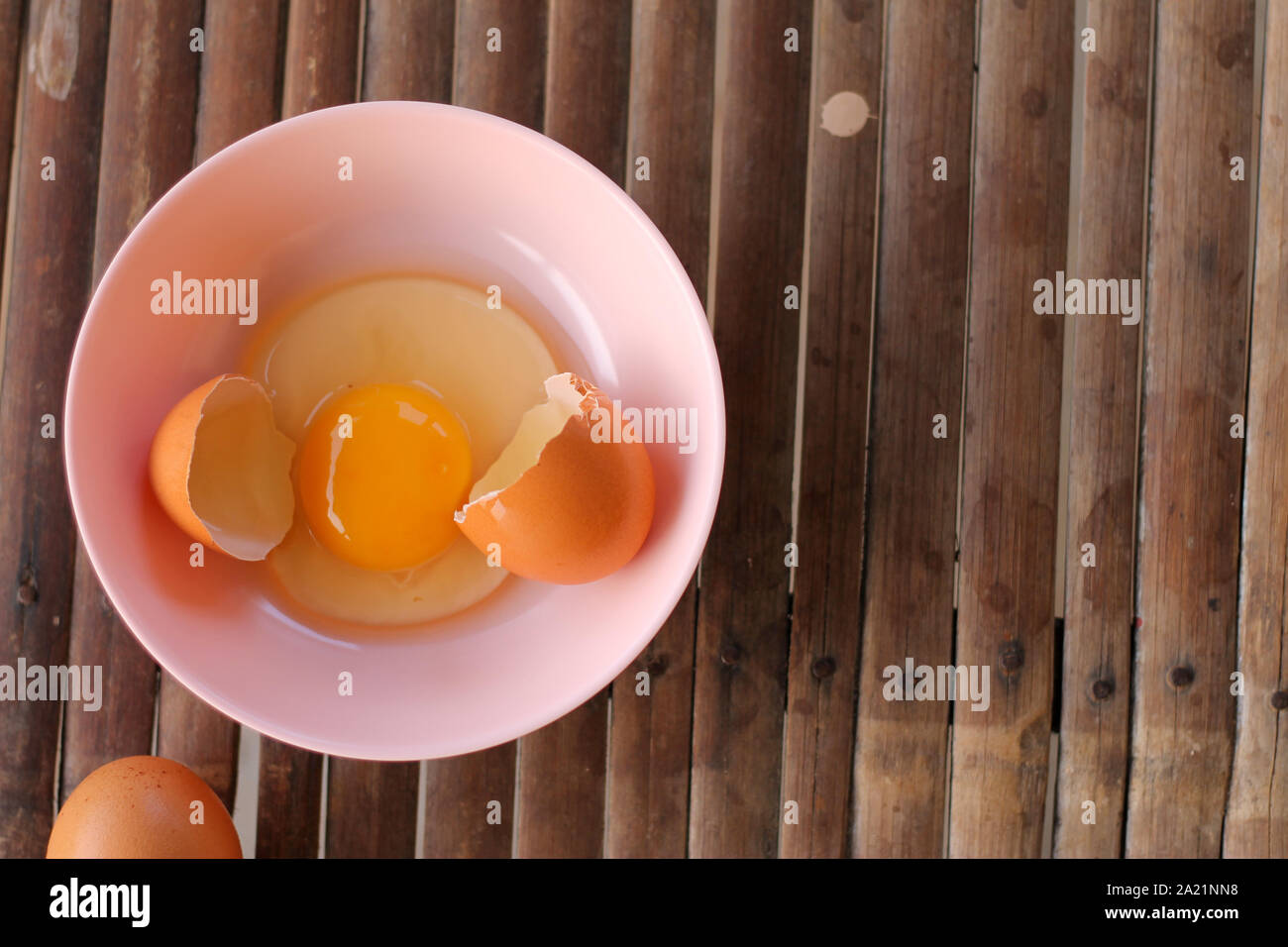 shell with egg and open Eggs in a pink bowl on Bamboo battens. Top view ...