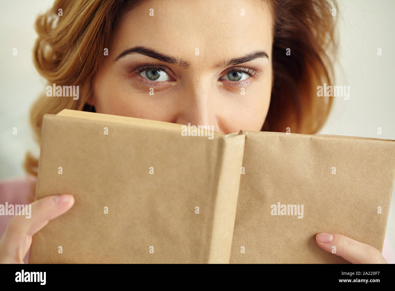 young woman looking over a book. reading and eyes Stock Photo - Alamy