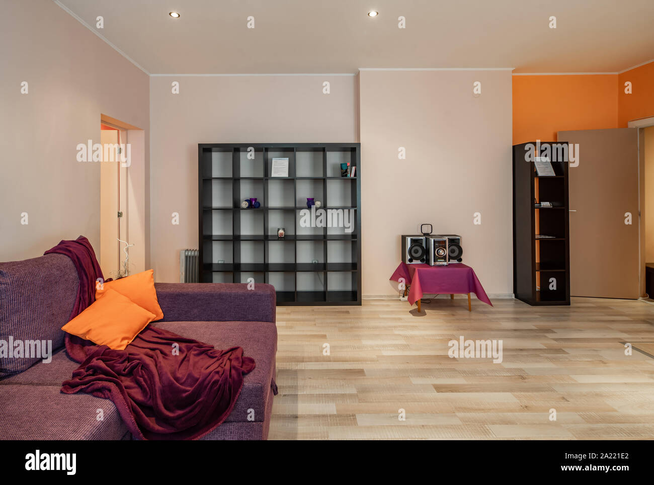 Cozy sofa. Shelves. Laminate floor. Orange pillows Stock Photo - Alamy