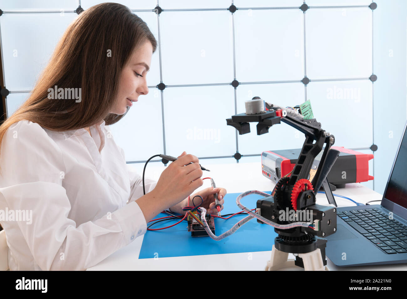 A young woman writes an algorithm for the robot arm. Science Research ...