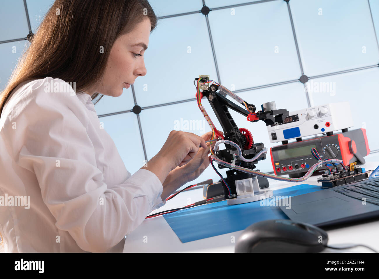 A young woman writes an algorithm for the robot arm. Science Research ...