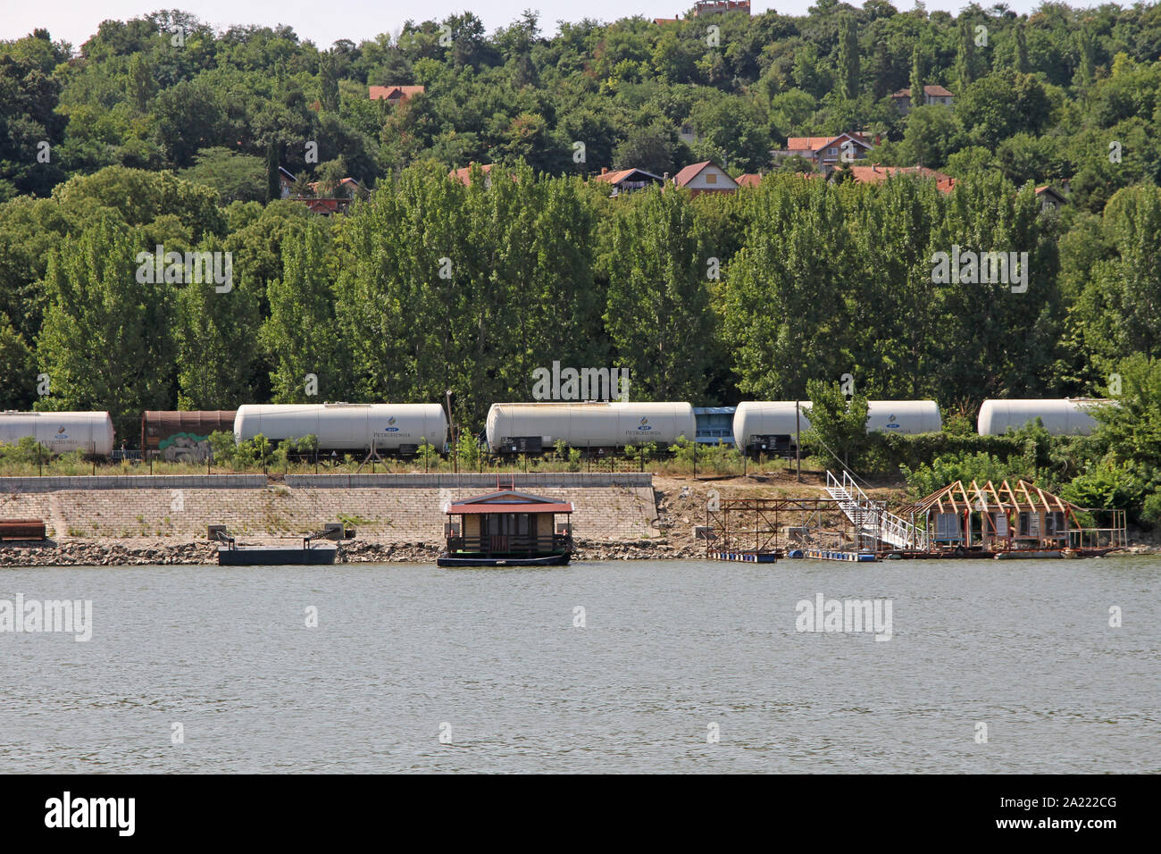 Petrol tanker trains and trees on the bank of the Danube River ...