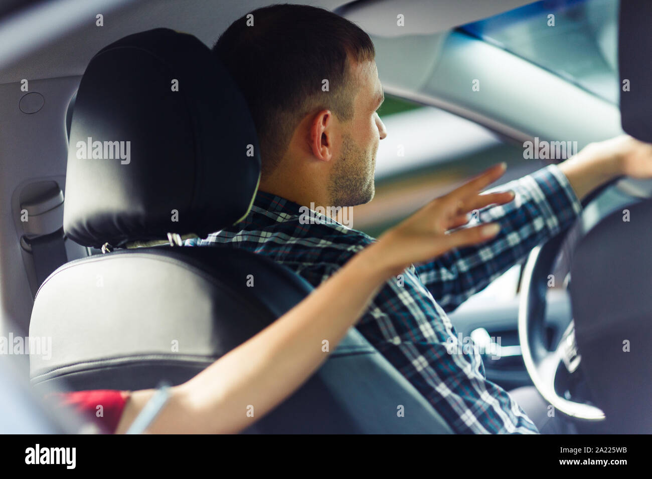 Photo from back of driver behind wheel and passenger pointing his hand ...