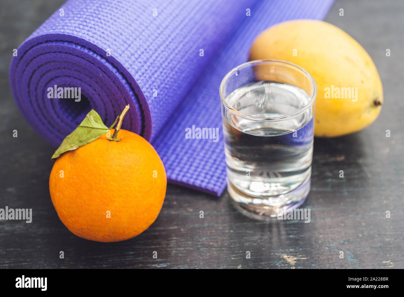 Yoga mat, water, orange and mango on a wooden background. Equipment for ...