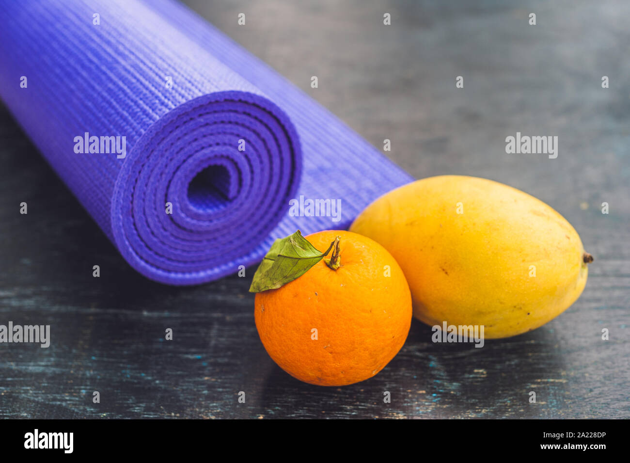 Yoga mat, water, orange and mango on a wooden background. Equipment for ...