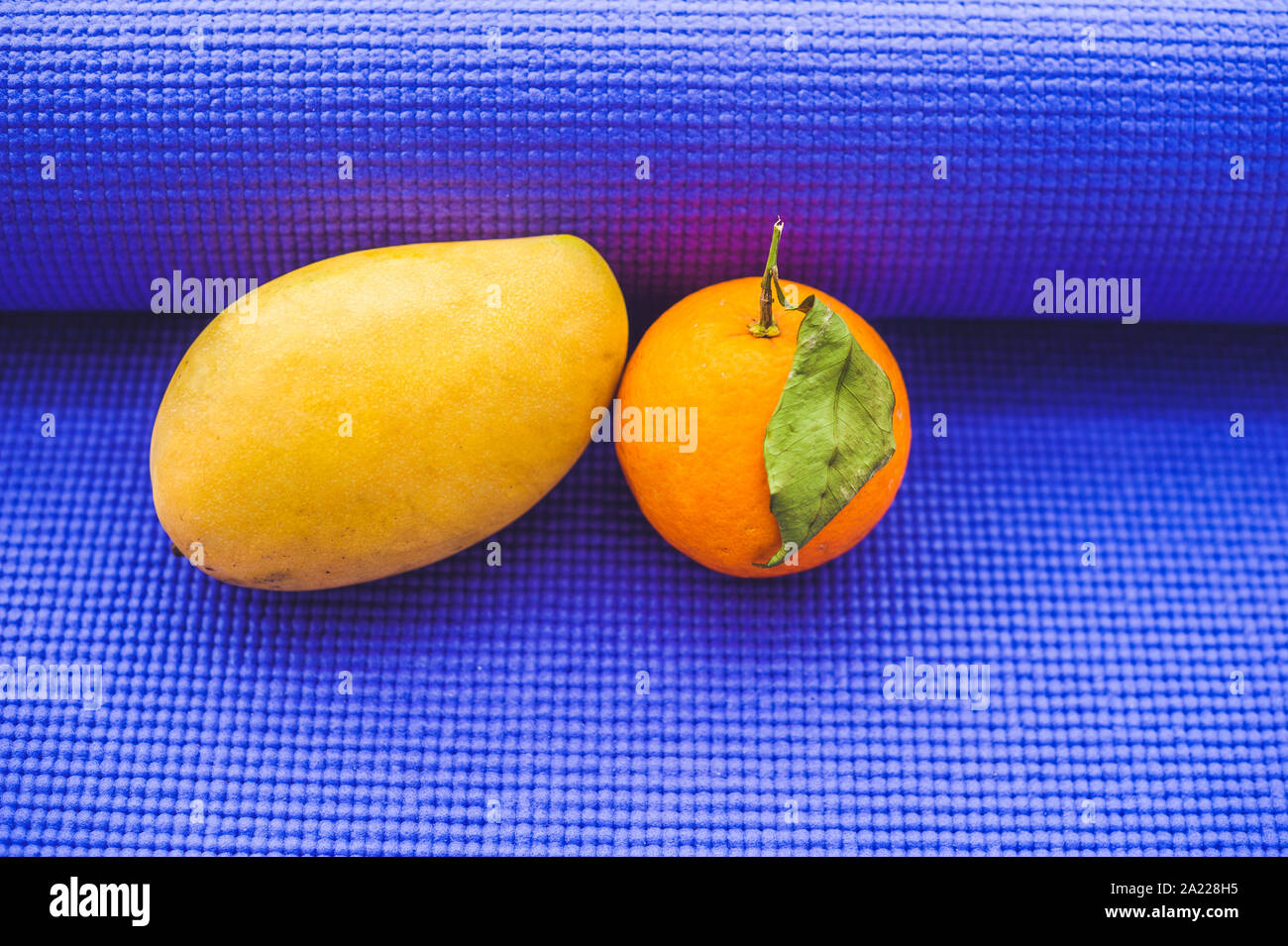 Yoga mat, water, orange and mango on a wooden background. Equipment for ...